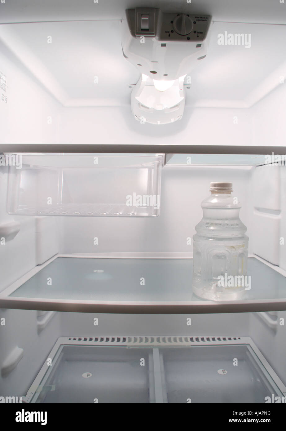 interior of empty shelves in refrigerator with one clear glass bottle ...