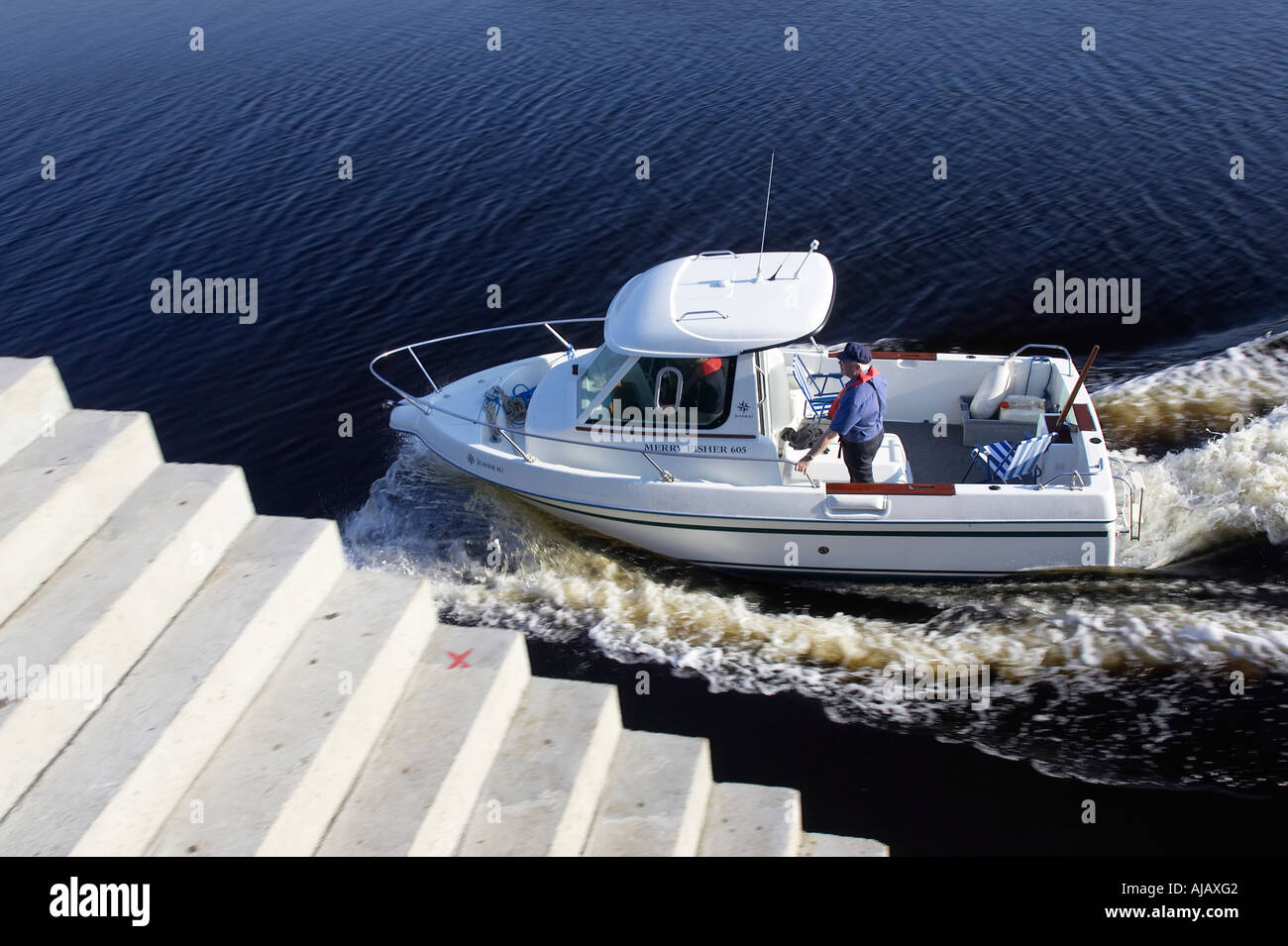 small white pleasure fishing boat sails past concrete quay steps into ...