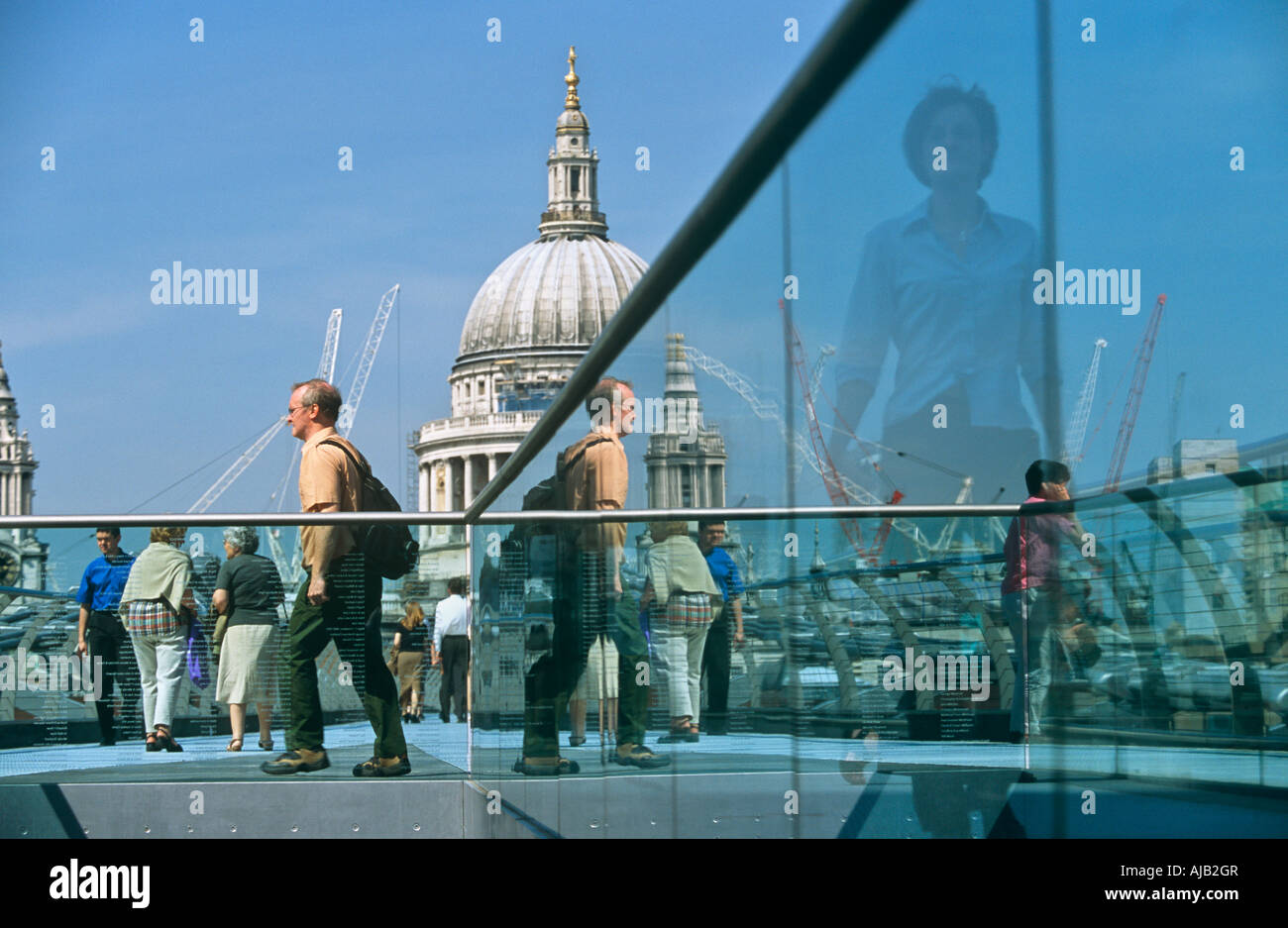 Pedestrians walk over the Millennium Bridge with St Pauls Cathedral in ...