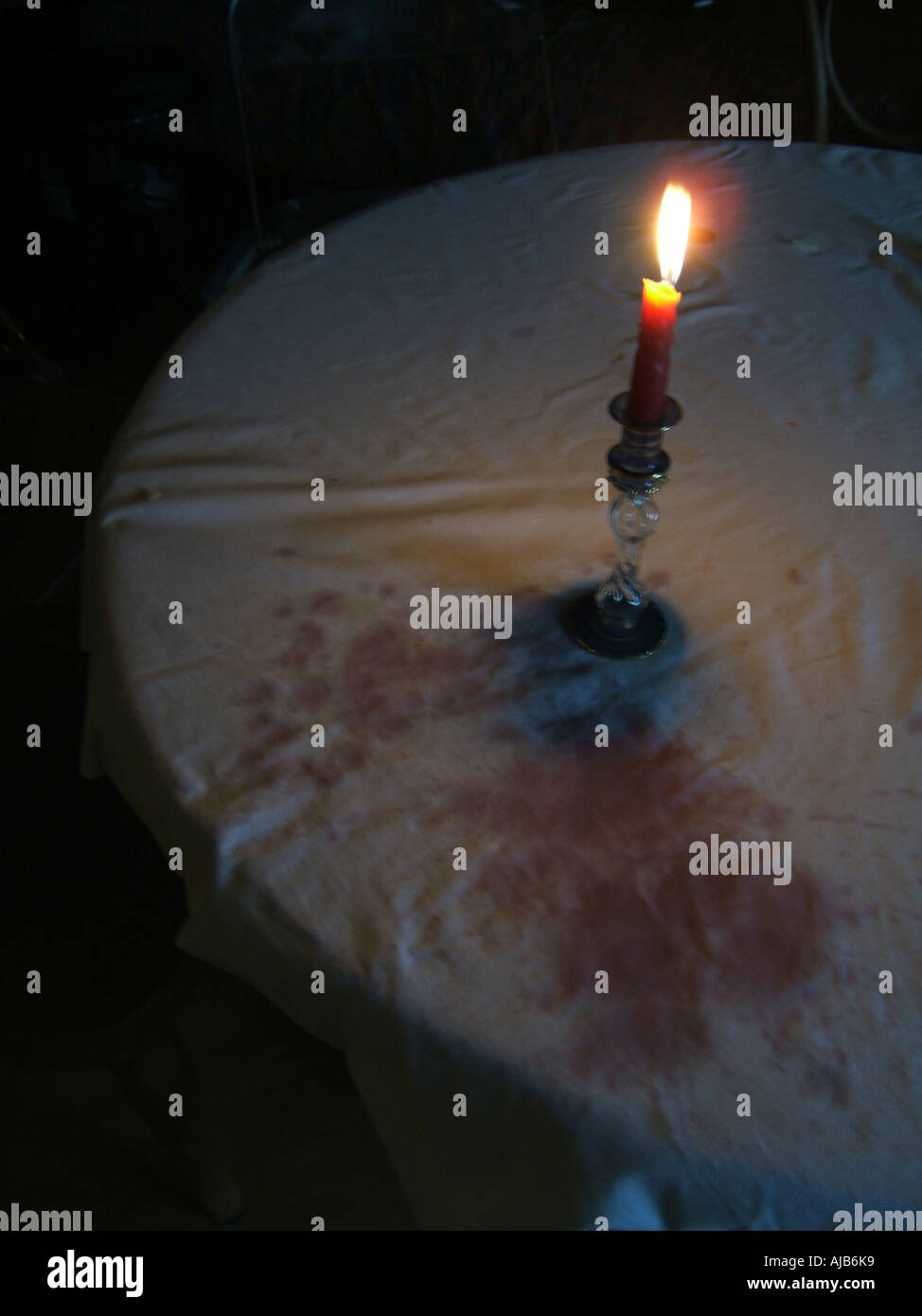 candle and spilt glass on dirty round table at night Stock Photo - Alamy
