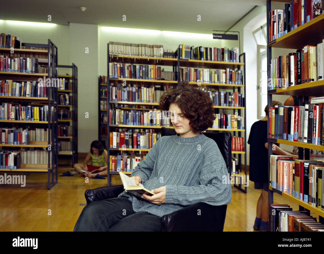 Girl reading a book in a public library Stock Photo - Alamy