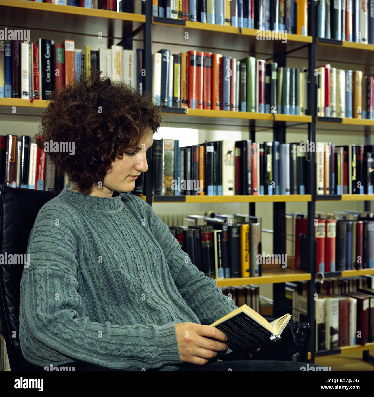 Girl reading a book in a public library Stock Photo - Alamy