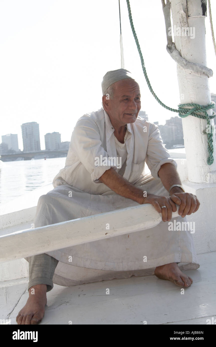 Egyptian boat man in traditional galibeya robe rowing Felucca sailing ...
