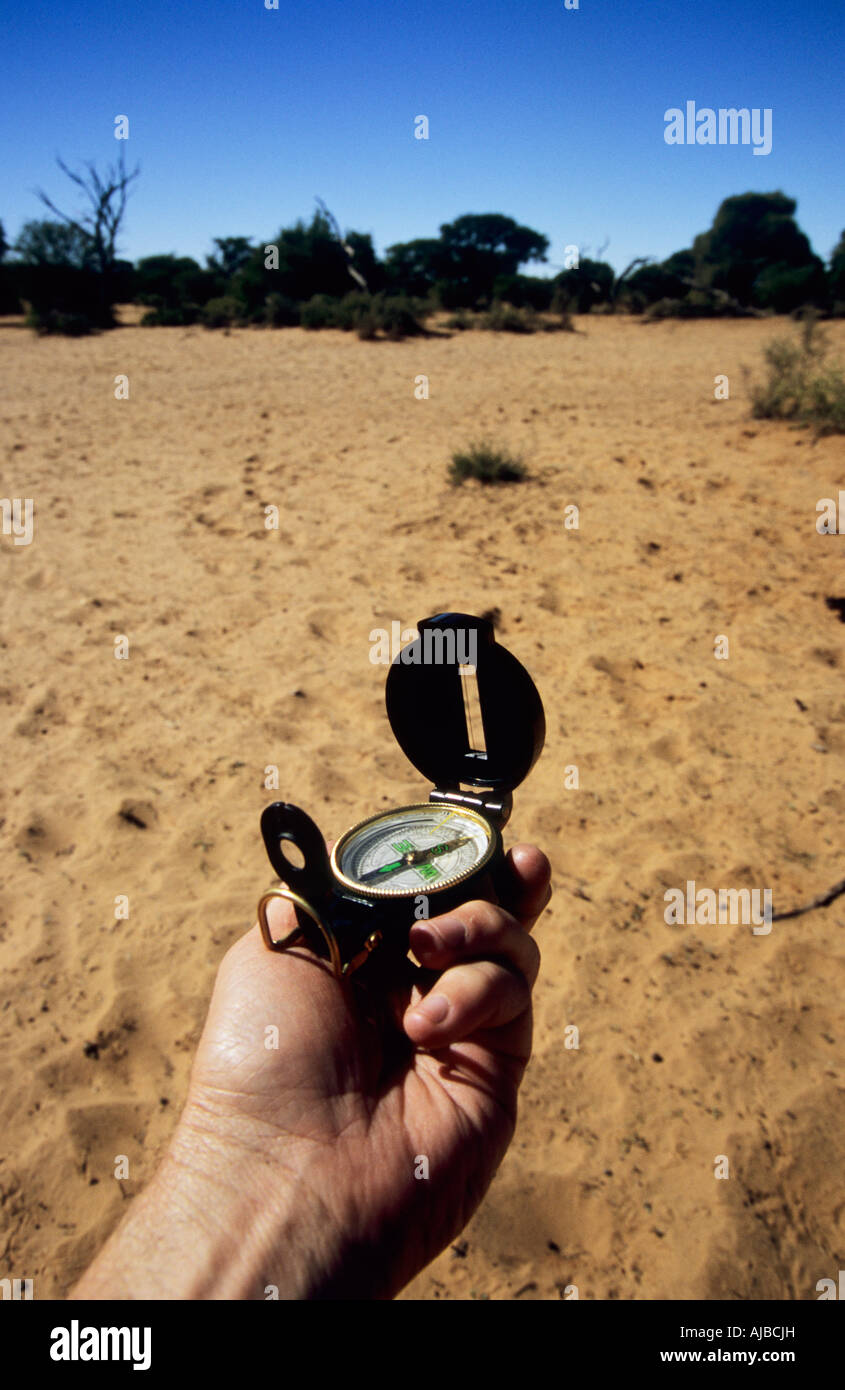 Compass in hand of adult man taking reading in arid semi-desert ...