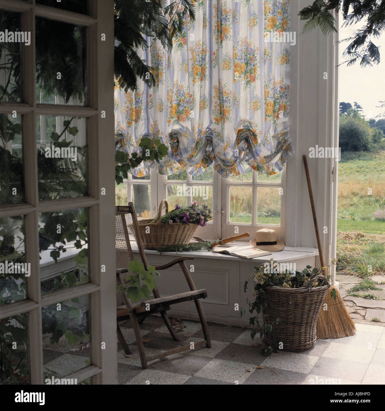 Old wooden lounger beside window with yellow+white floral festoon blind ...