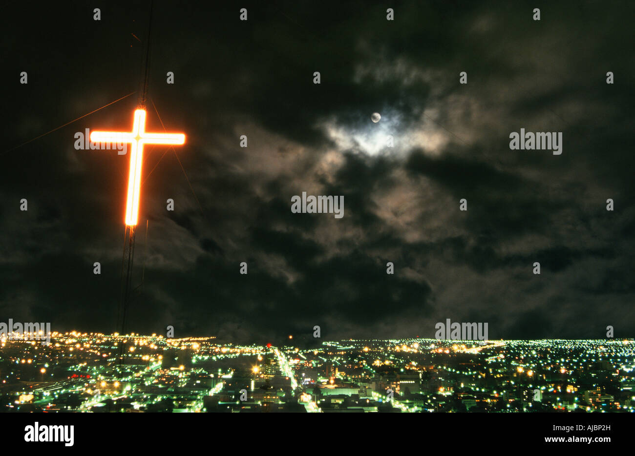 Illuminated Cross Over City Lights with Moon Shining Through Cloud ...