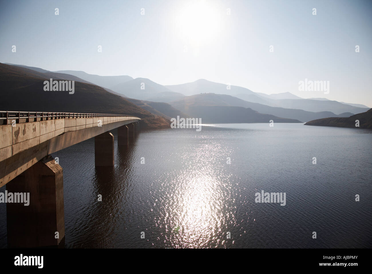View of Bridge Going Over Katse Dam with Sun Reflecting Off Water Stock ...
