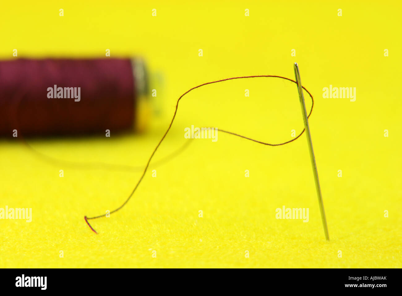 needle with redish string in yellow background sewing handcrafted ...