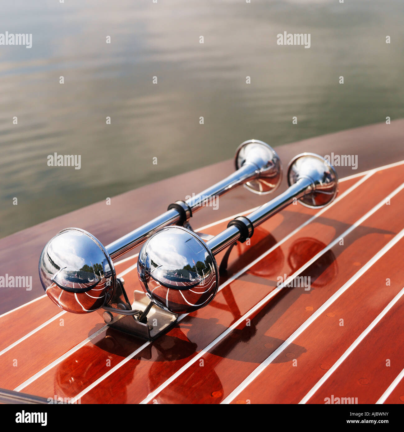 Detail of dual chrome trumpet horns on wooden boat floating in water ...