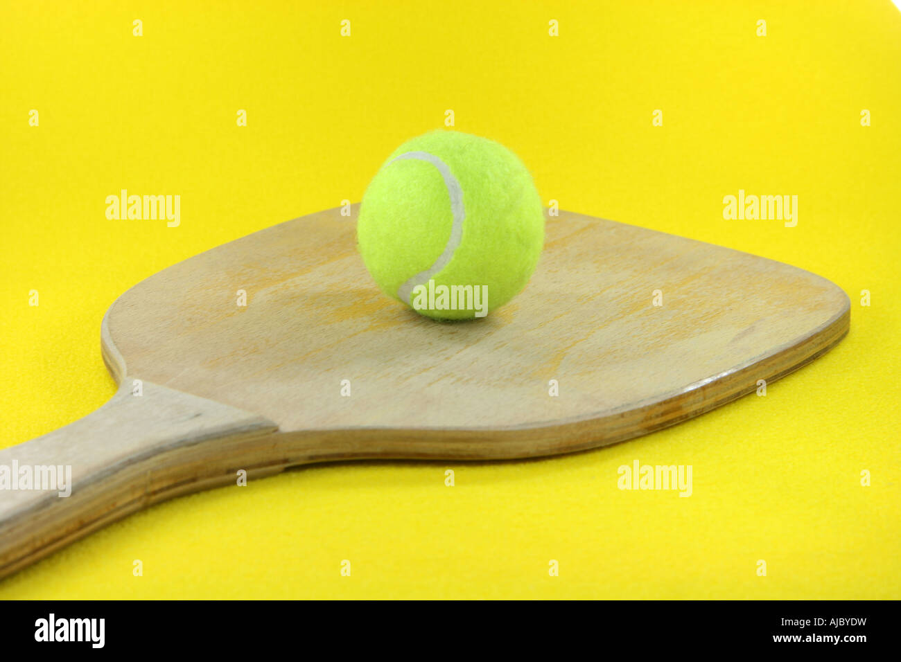 beach wooden racket with yellow ball in yellow background prespective ...