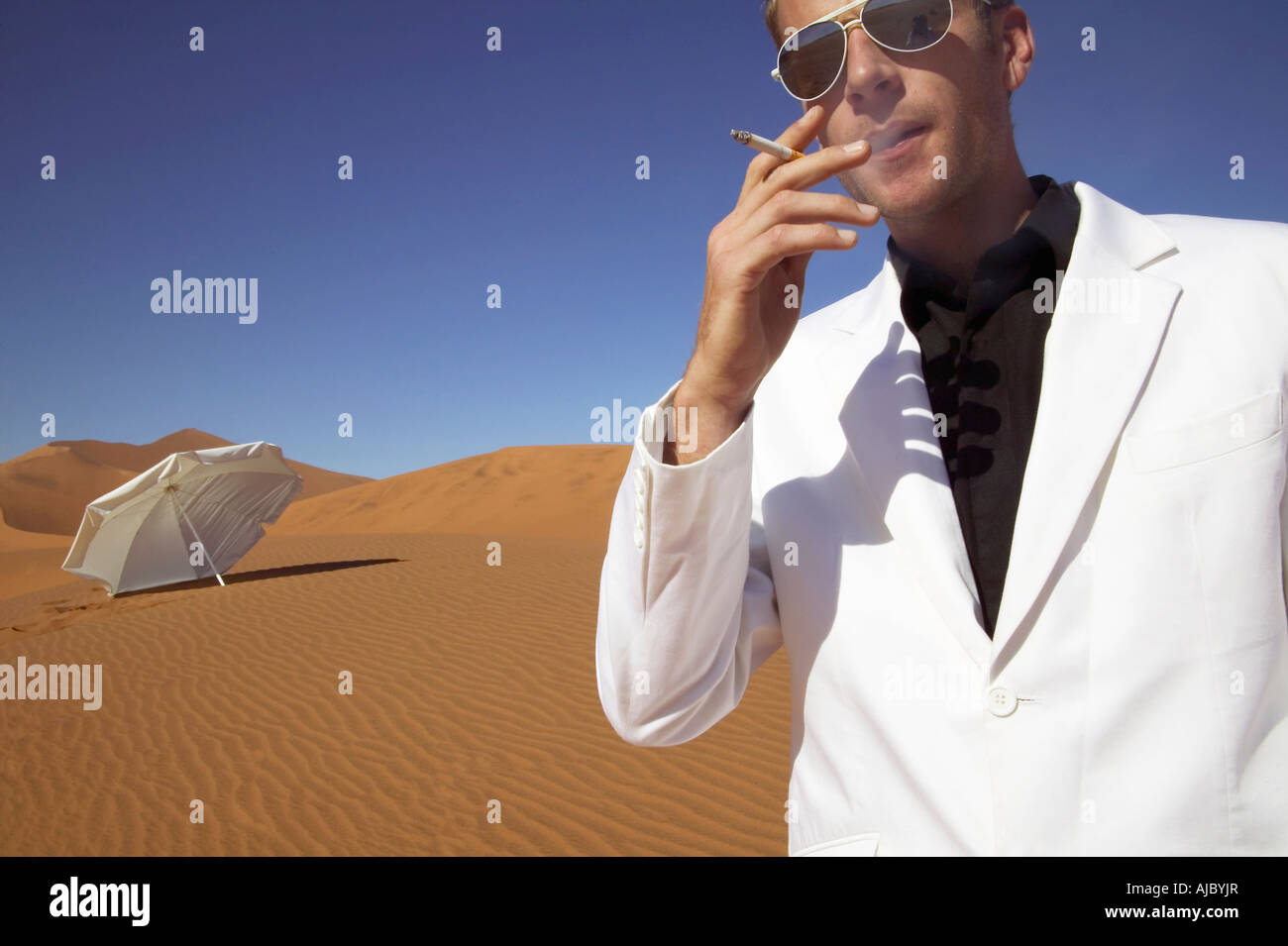 Man in a White Suit, Smoking a Cigarette in the Dessert Stock Photo - Alamy
