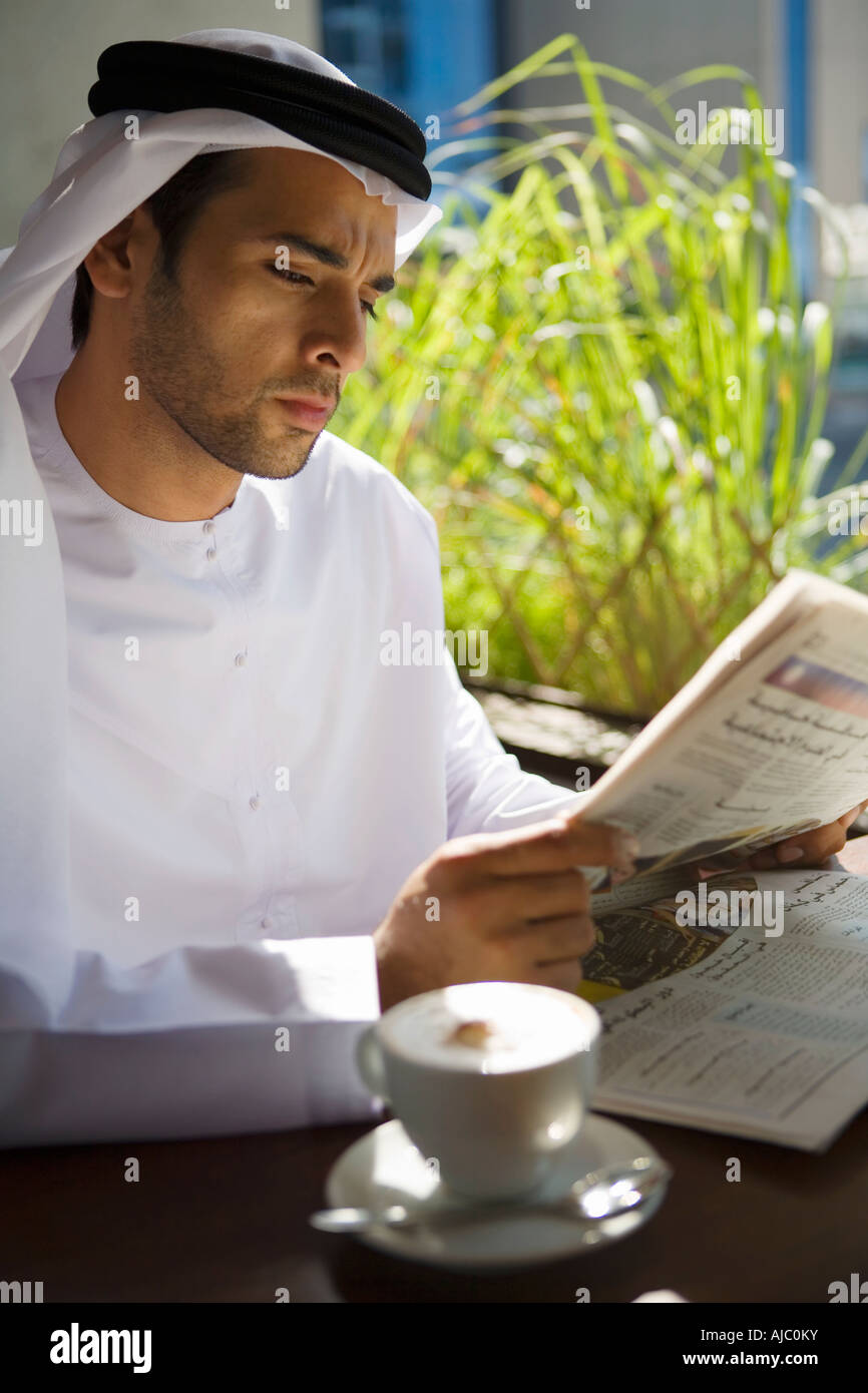 Arab Man Reading Newspaper in Cafe with Cappuccino Stock Photo - Alamy