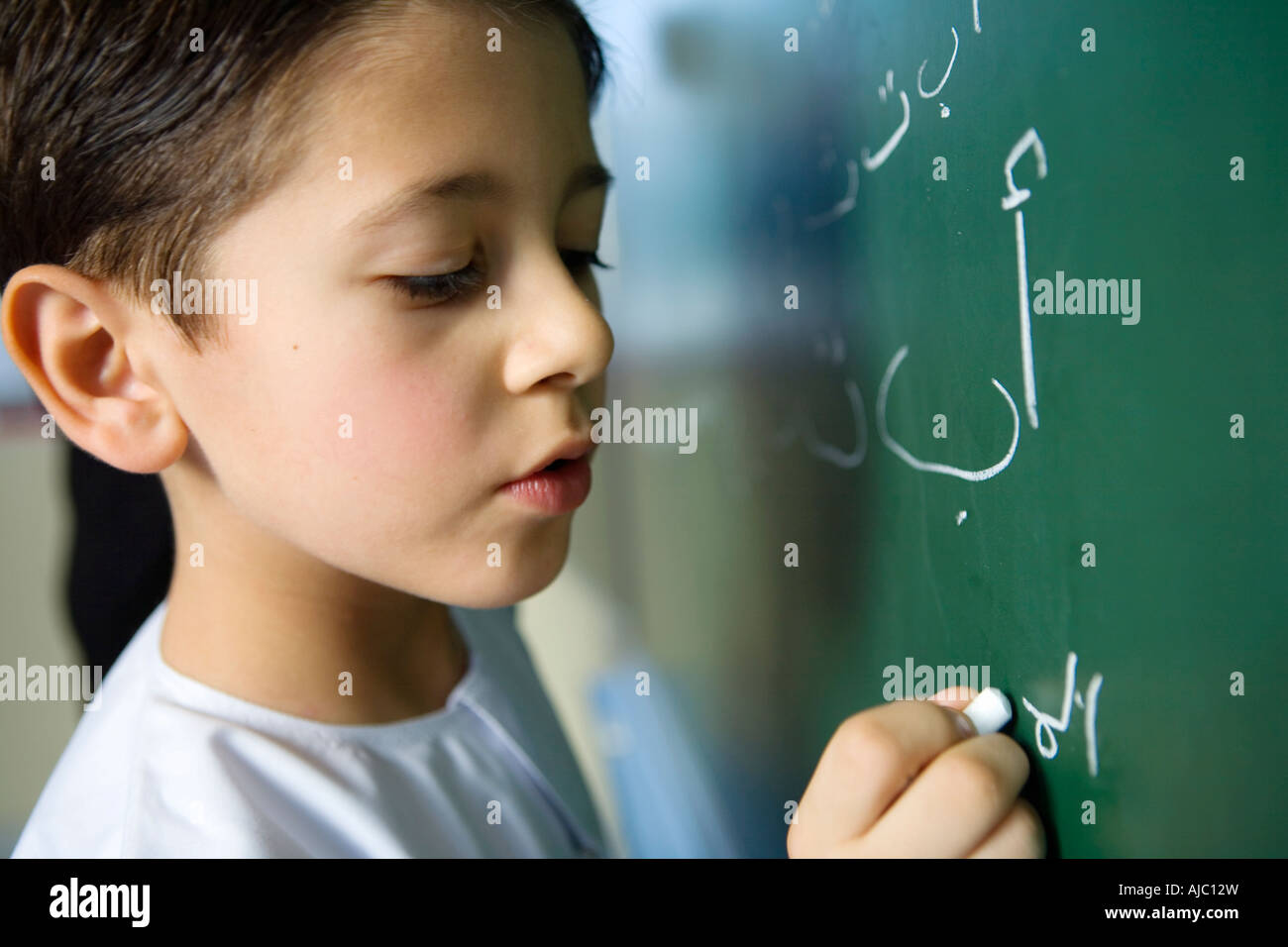 Boy writing on blackboard in classroom hi-res stock photography and ...