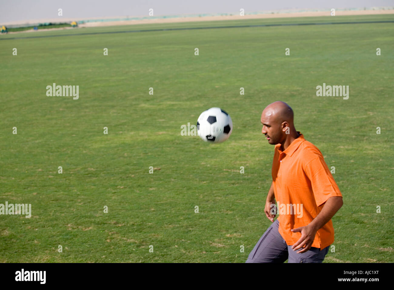 Arab man playing football on football field, side profile view Stock ...