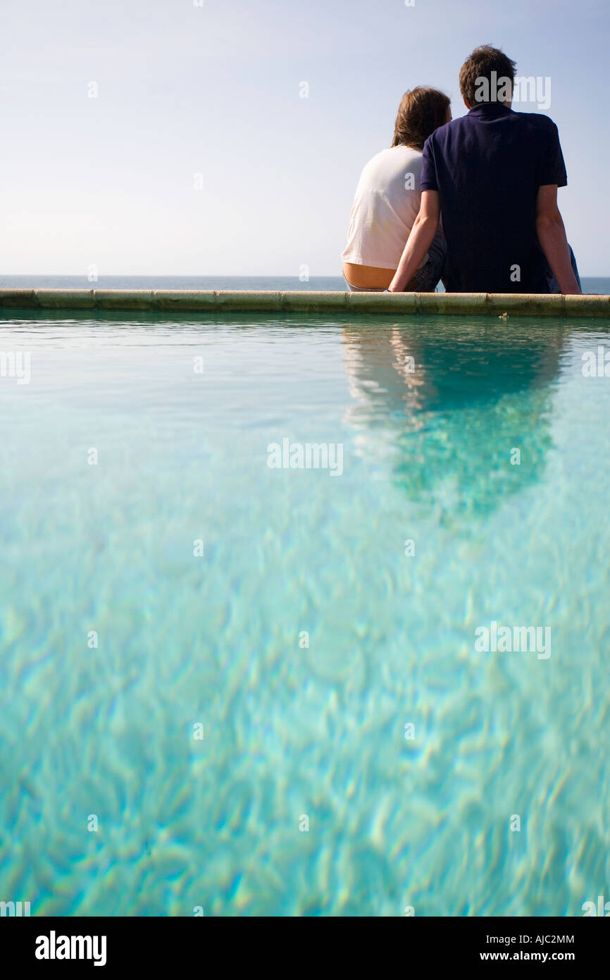 Couple Sitting on Edge of Swimming Pool Stock Photo - Alamy