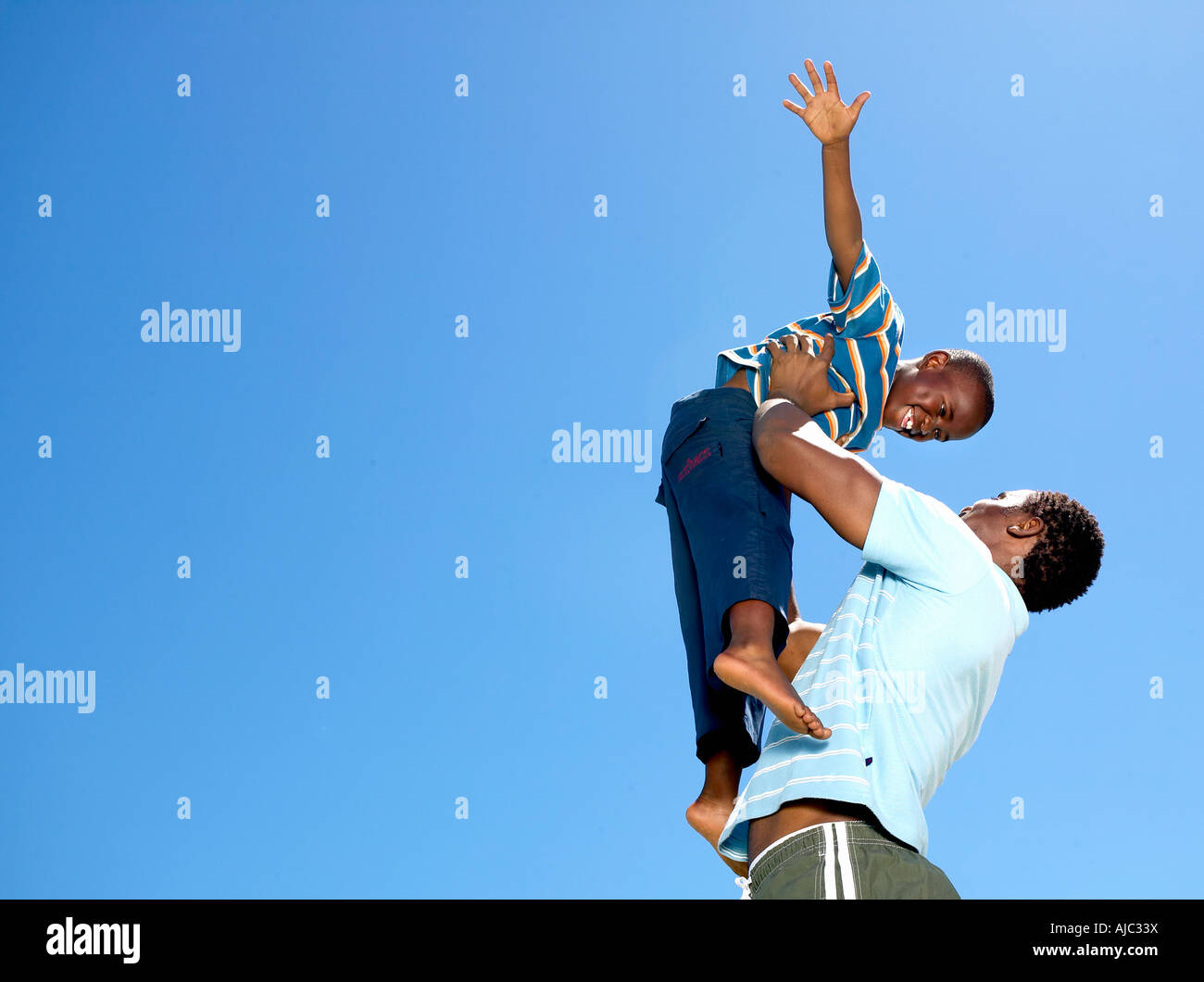 African Man Lifting his Son - Low Angle View Stock Photo - Alamy