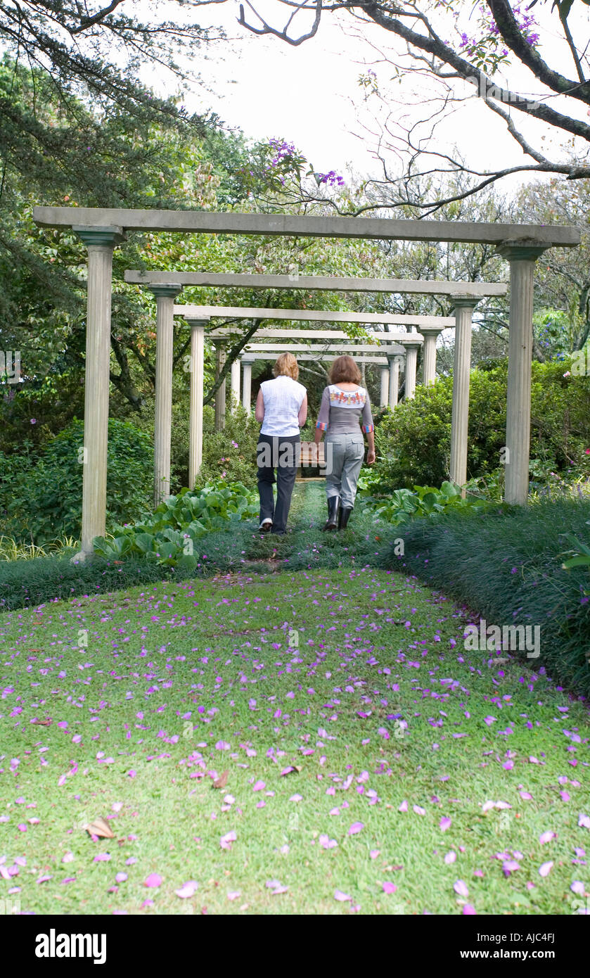 Rear View of Two Women Walking Along Arched Pathway Stock Photo - Alamy
