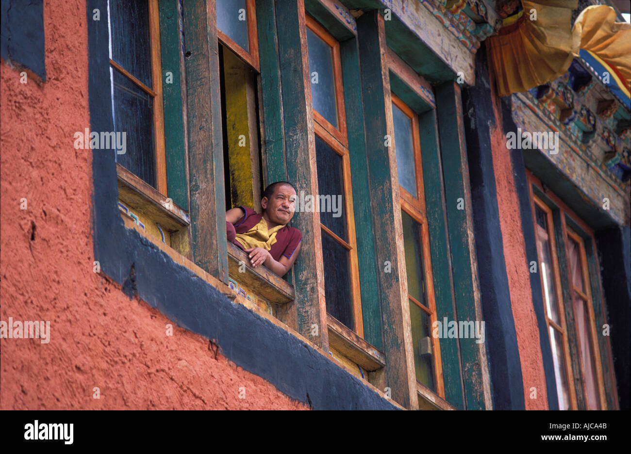 Monk leaning from the window of the great hall Thikse Monastery Ladakh ...