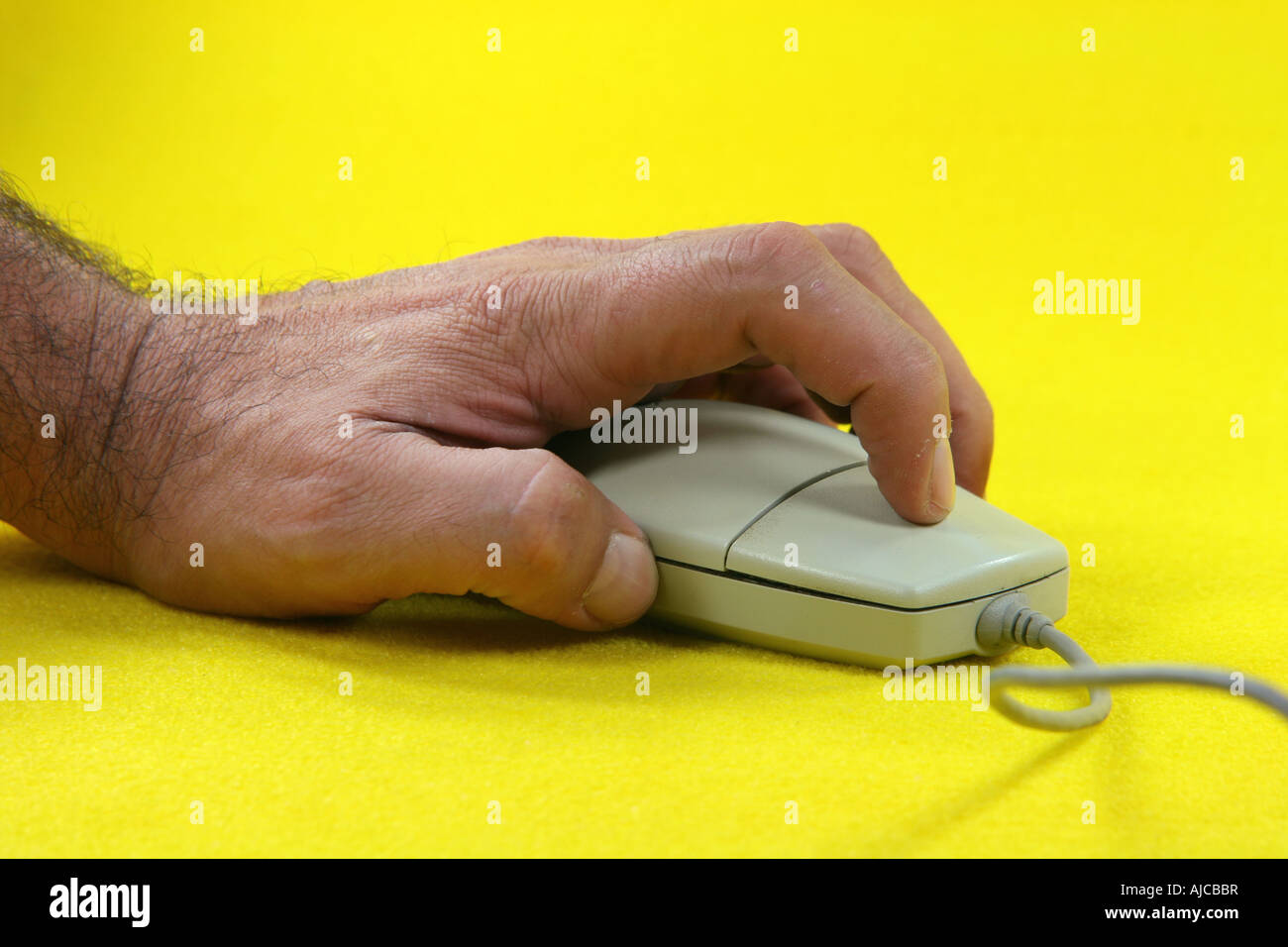 hand clicking a mouse in yellow background Stock Photo - Alamy