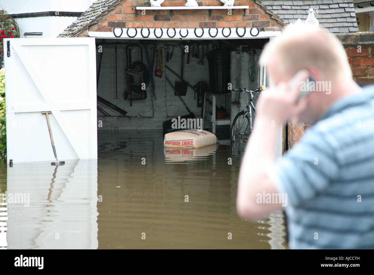 Man standing in front of a flooded garage with the doors wide open and ...
