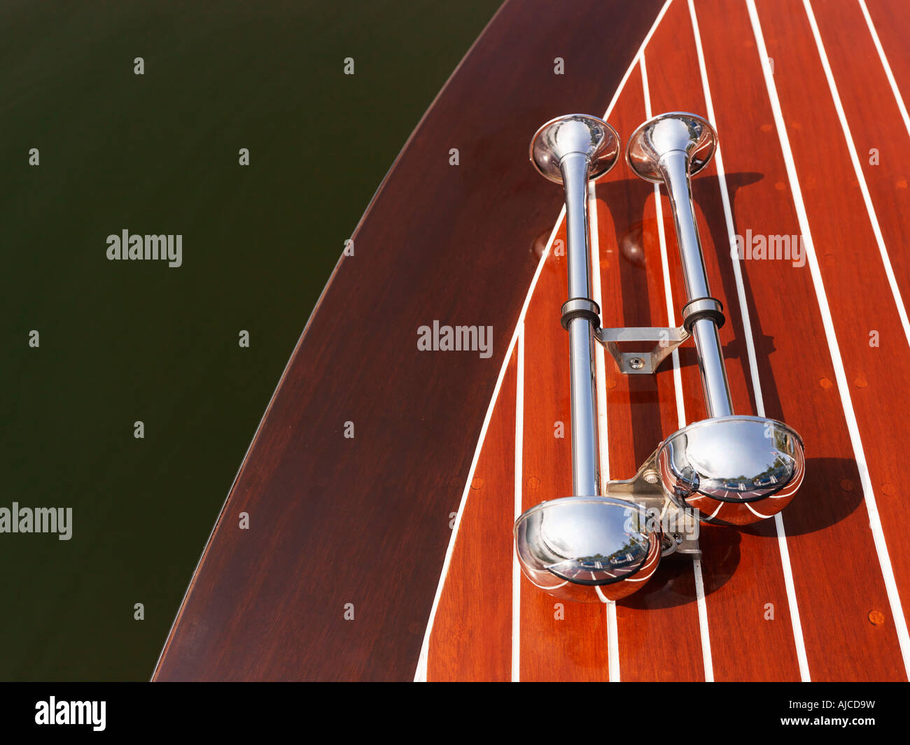 Detail of dual chrome trumpet horns on wooden boat floating in water ...