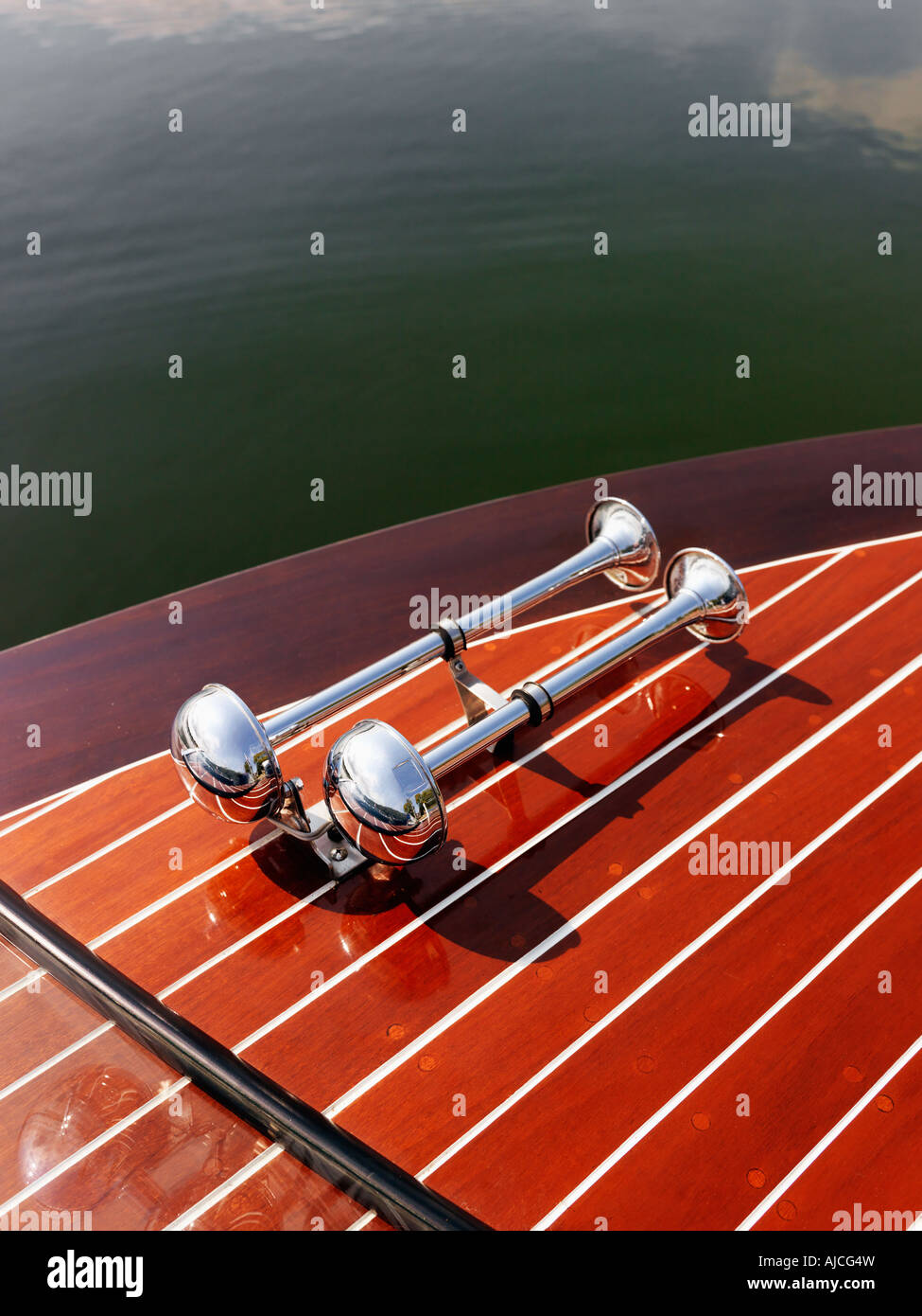Detail of dual chrome trumpet horn on wooden boat floating in water ...