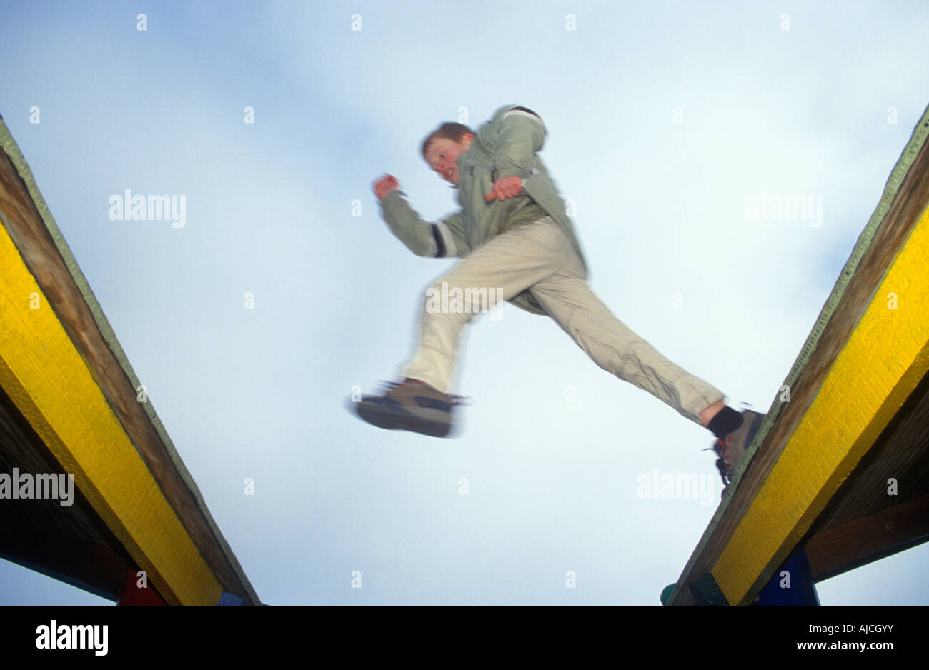 a young boy jumping across a gap Stock Photo - Alamy