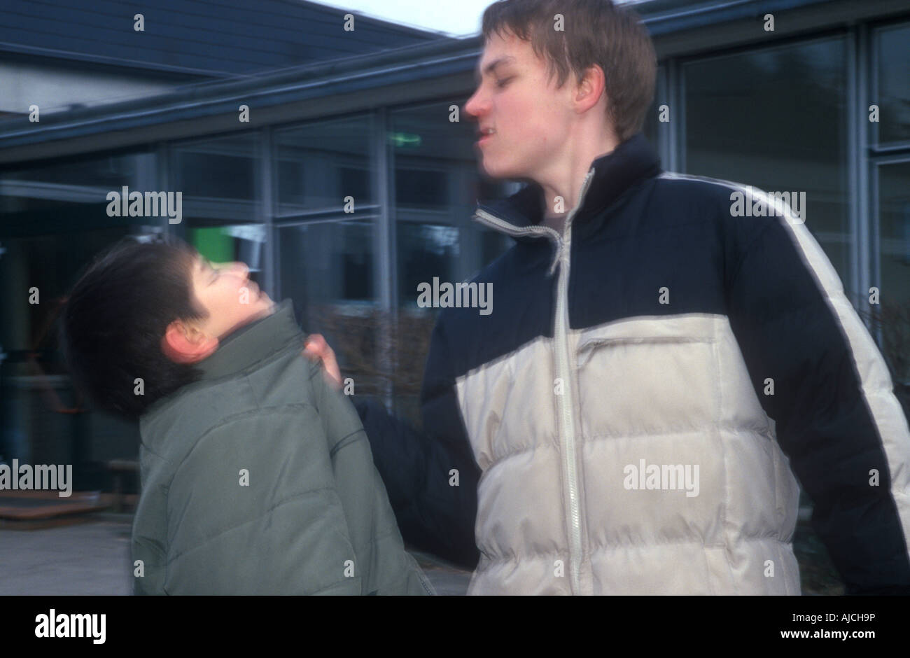 a teenage boy choking a younger one at a schoolyard Stock Photo - Alamy