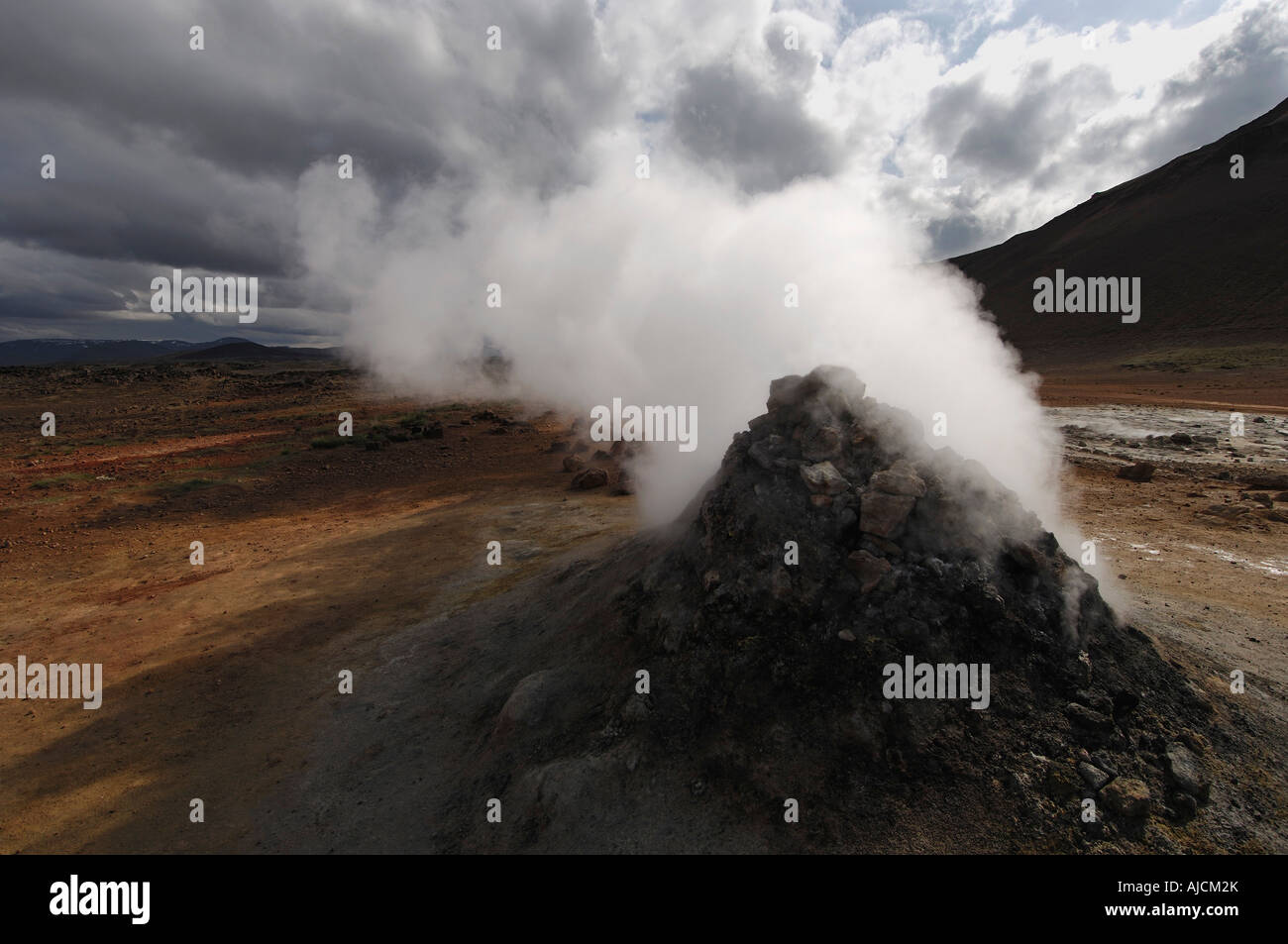 Steaming vent or fumarole in a geothermal landscape with a view of ...