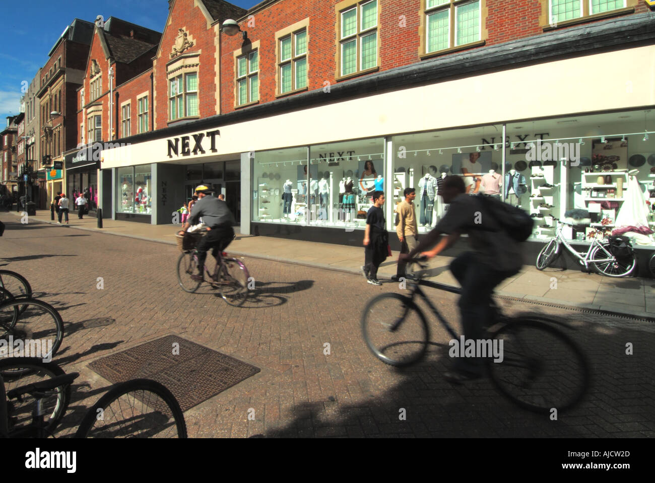 Cambridge branch of Next clothing store with cyclists passing at speed ...