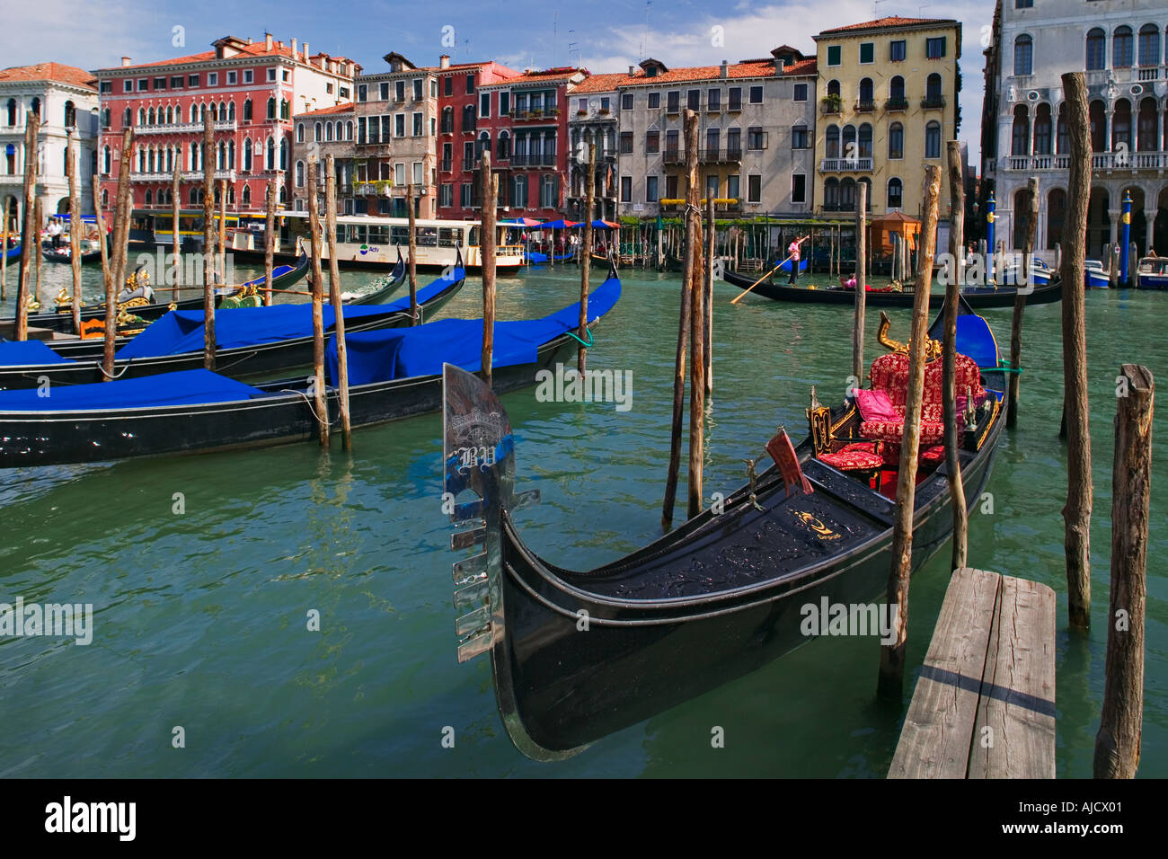 Gondolas tied to old wooden docks on the Grand Canal near Ponte (Rialto ...