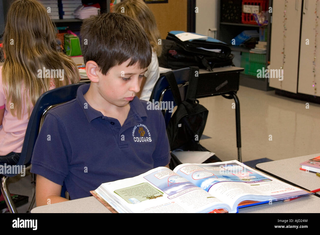Fourth grade student reads a textbook in a classroom at a public school ...