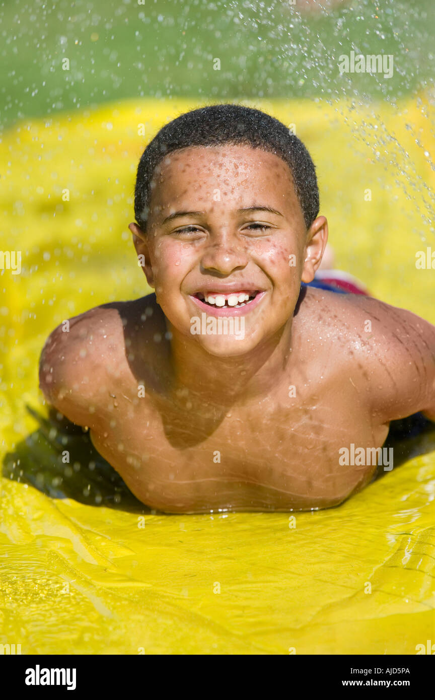 Boy (7-9) sliding on water slide, front view portrait Stock Photo - Alamy