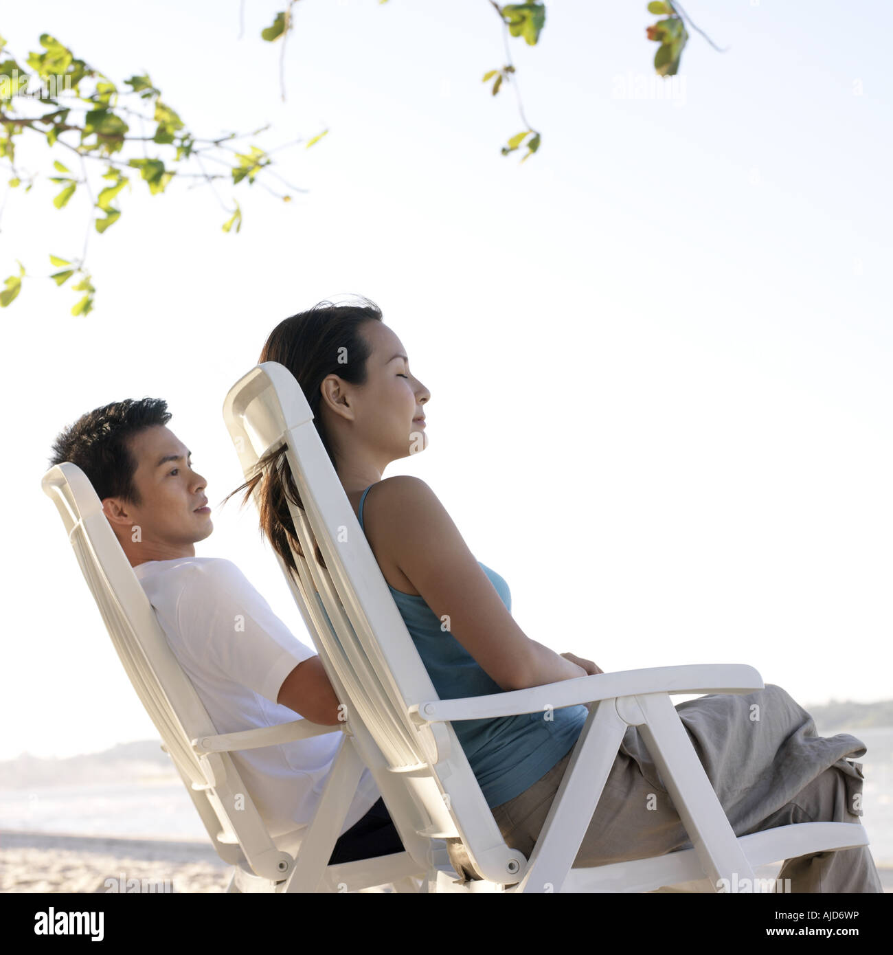 Couple sitting on deck chairs at beach Stock Photo - Alamy