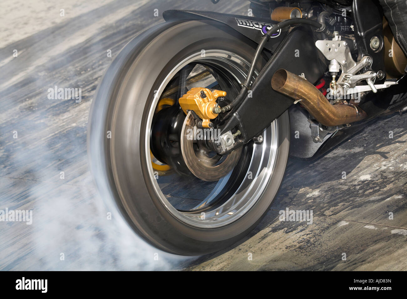 spinning motorcycle wheel and tyre creating burnout smoke at a drag ...