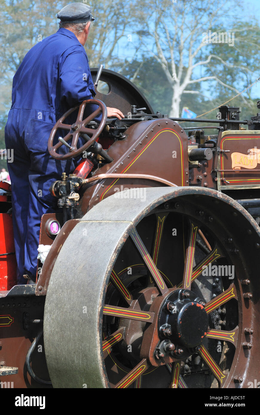 Man in a blue boiler suit at the controls of a vintage steam traction ...