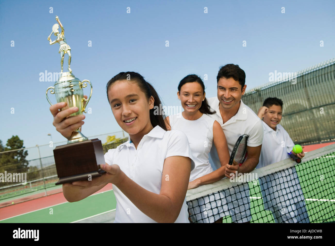 Tennis Family on court by net, daughter holding trophy, portrait Stock ...