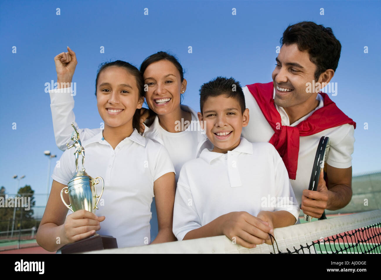Tennis Family at net on tennis court, daughter holding trophy, portrait ...
