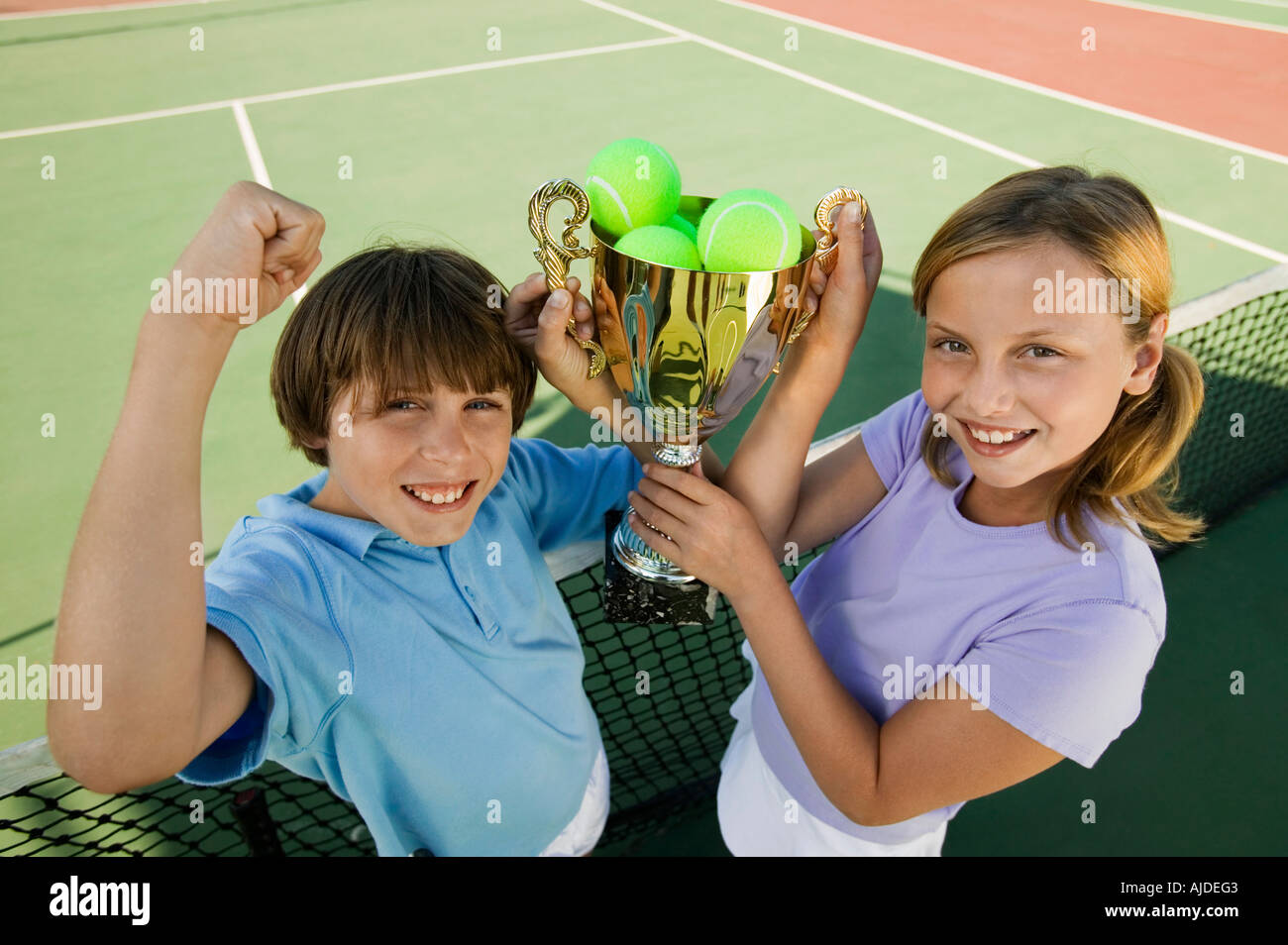 Brother And Sister On Tennis Court Holding Up Trophy Portrait High
