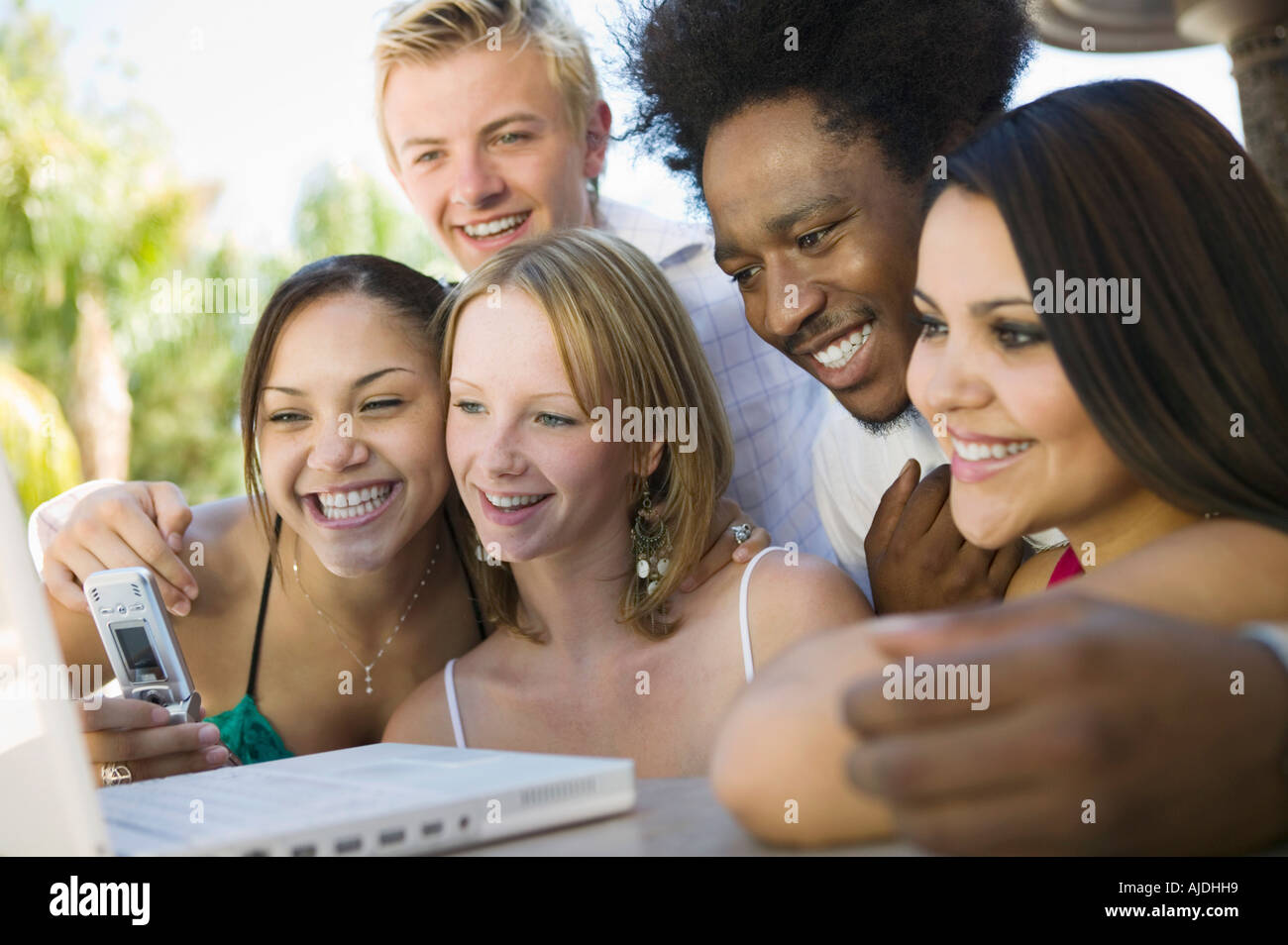 Group of friends at back yard table using laptop and cell phone, close ...