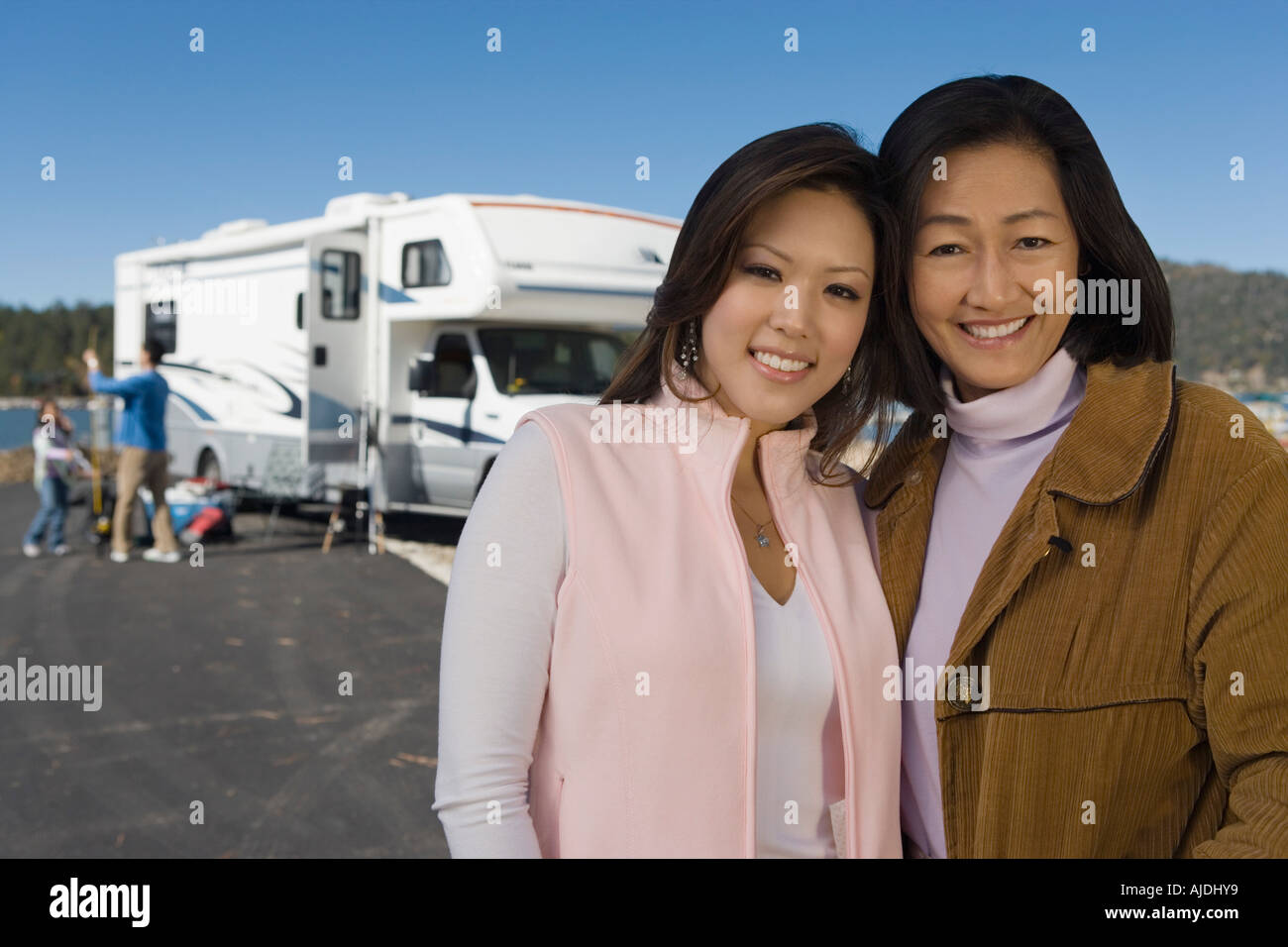 Mother and teenage daughter standing outside of RV at lake Stock Photo ...