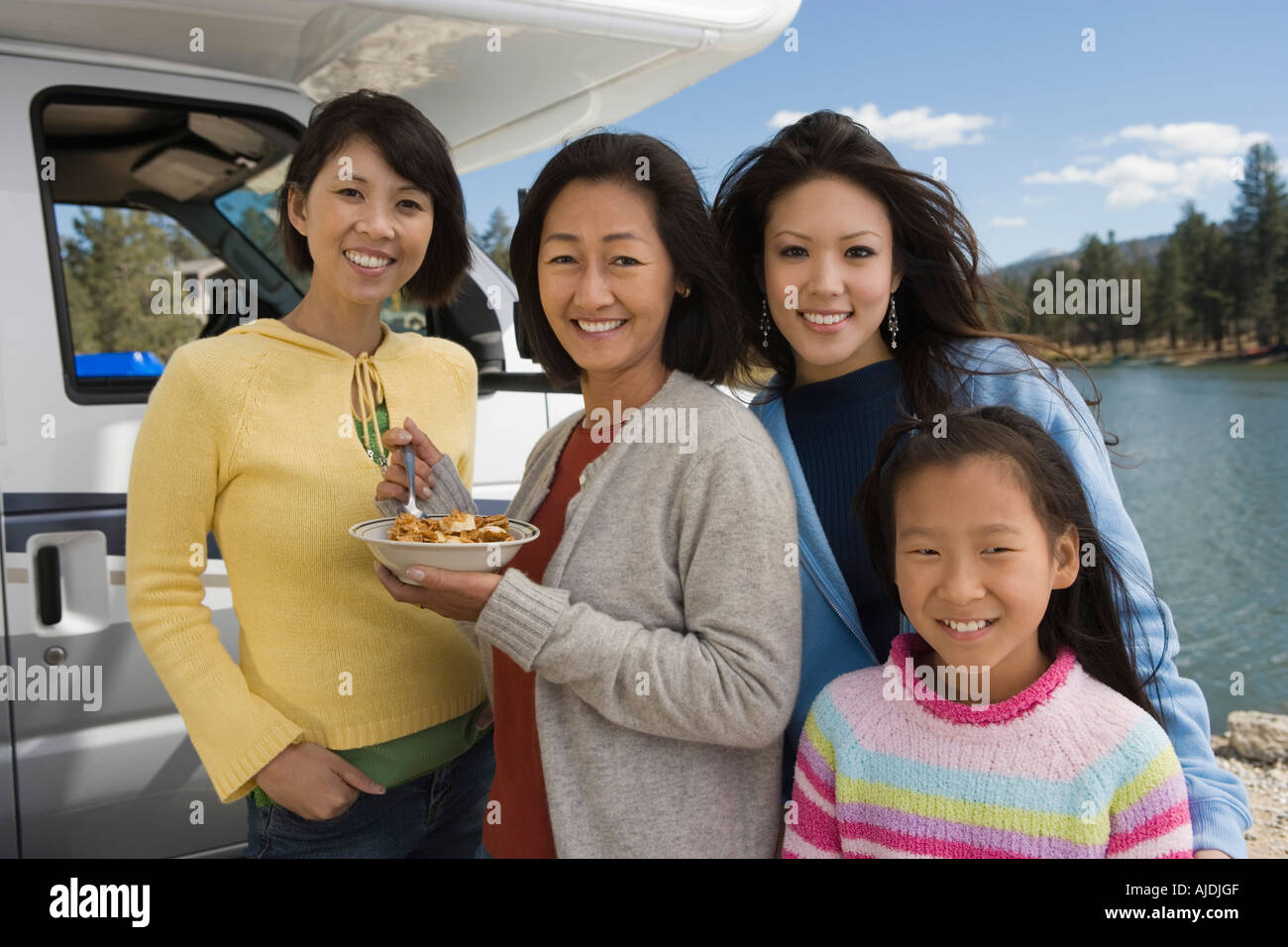 Three-generation of women eating breakfast outside of RV at lake Stock ...