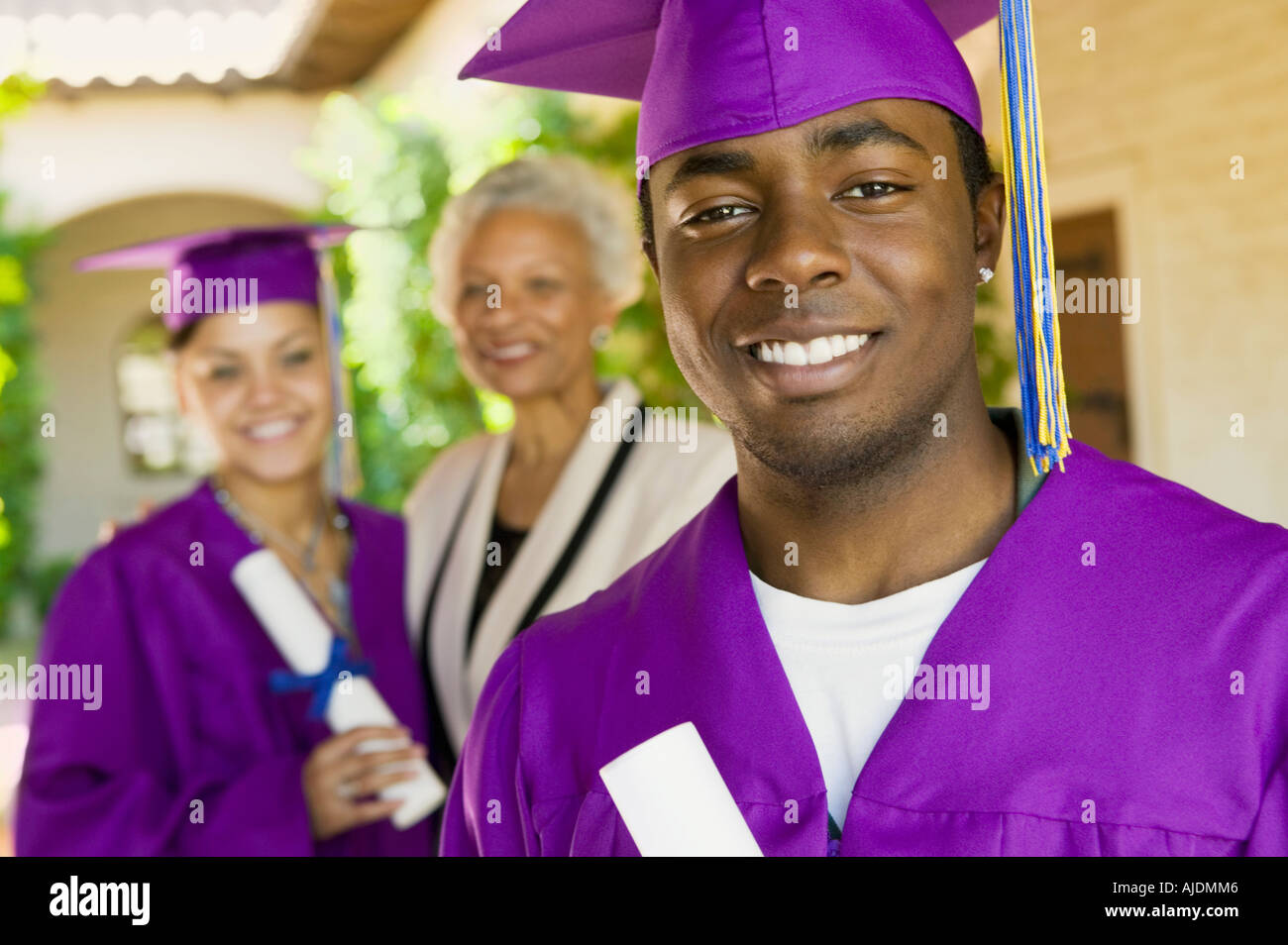 Graduate outside with second graduate and grandmother behind, portrait ...