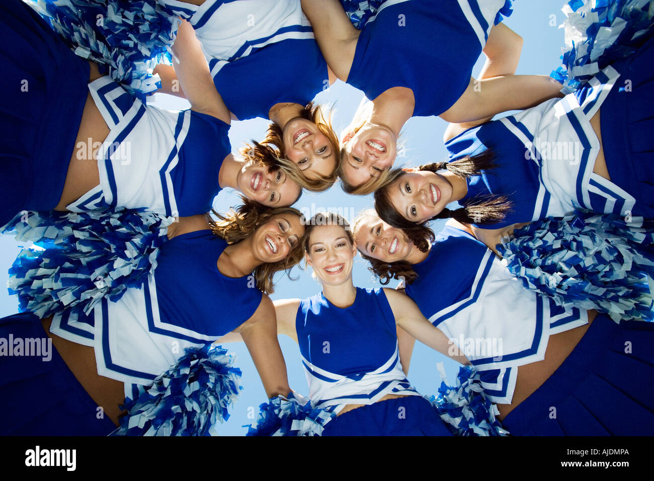 Smiling Cheerleaders standing in circle, (portrait), (view from below ...
