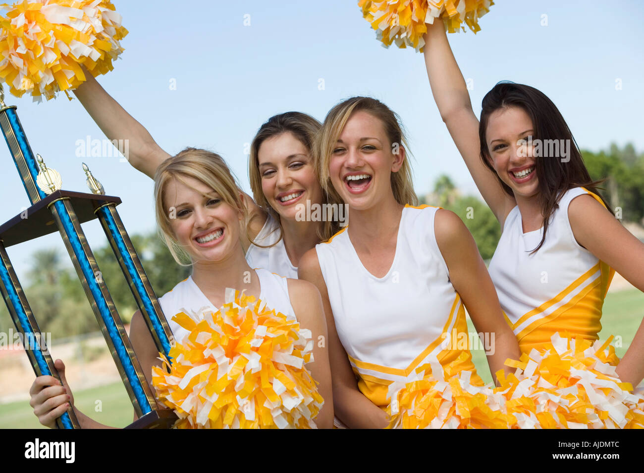 Smiling Cheerleaders holding trophy and pom-poms, (portrait Stock Photo ...
