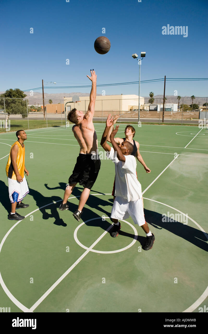 Young men reaching in air for basketball during game Stock Photo - Alamy