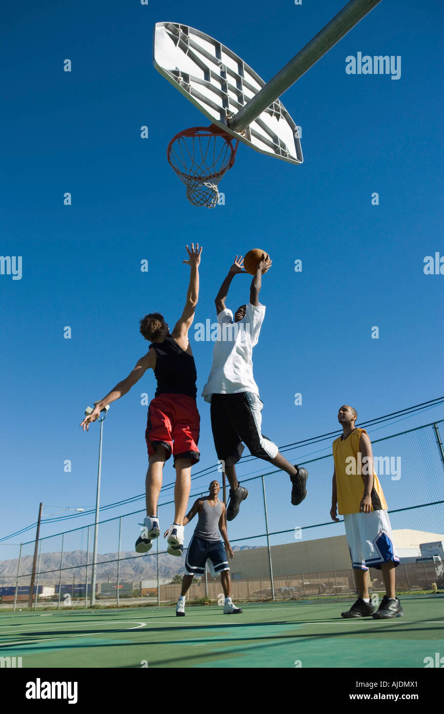 Basketball player, mid-air, shooting ball into hoop while another ...