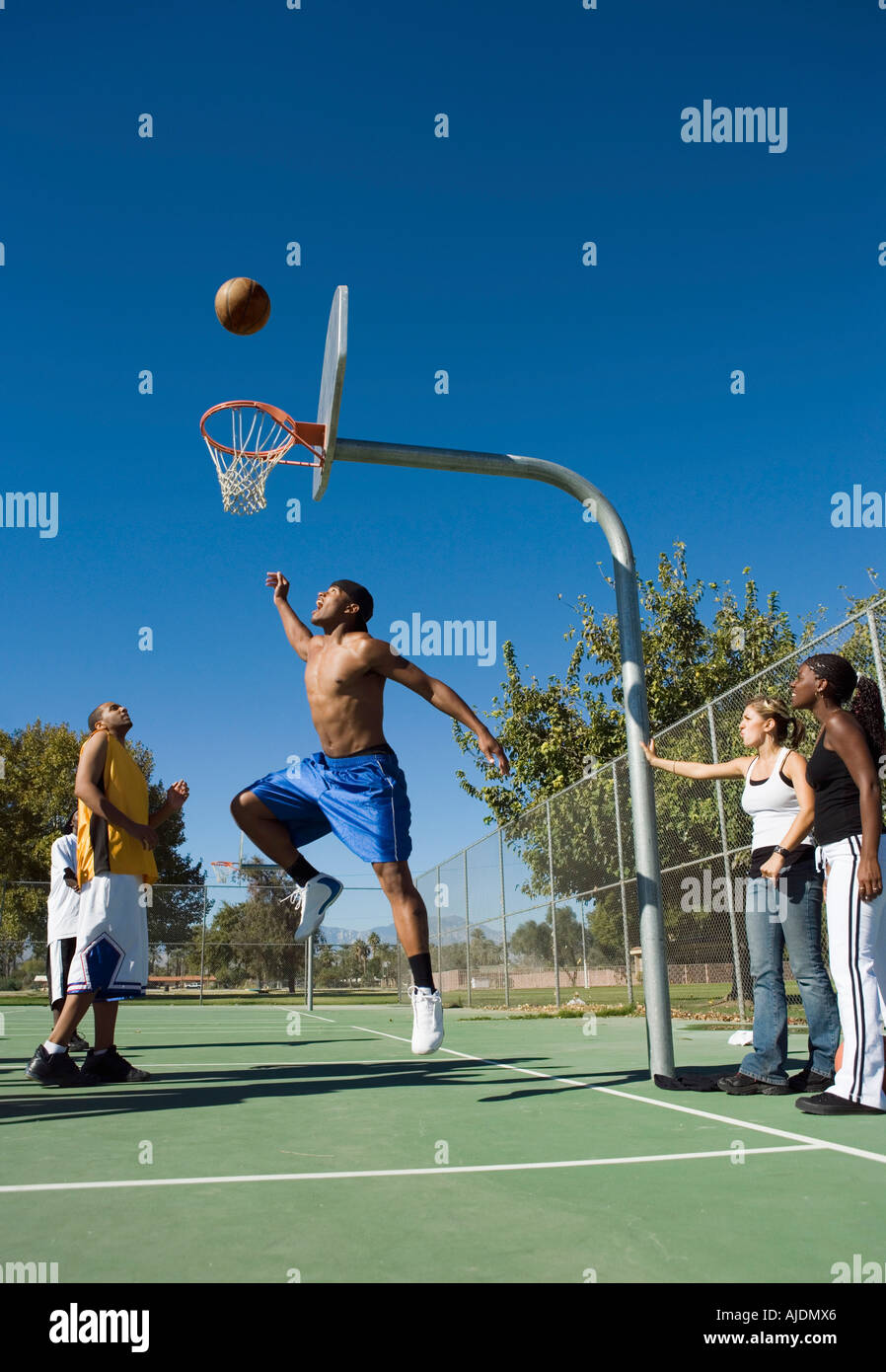 Group of young people playing basketball, one player jumping for ball ...