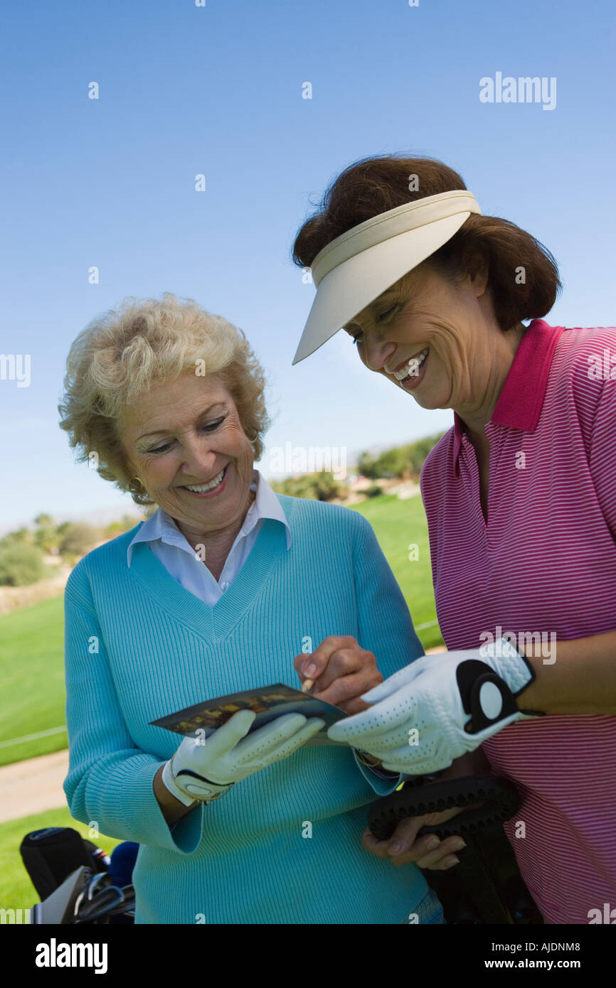 Two women writing in score card on golf course Stock Photo - Alamy