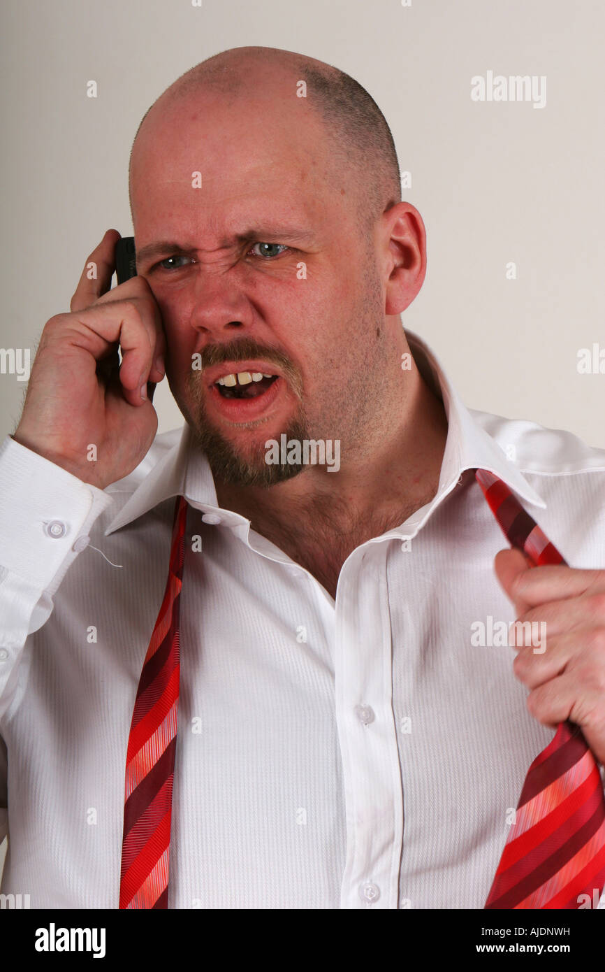 An angry man talking on a mobile phone in shirt and loose tie Stock ...